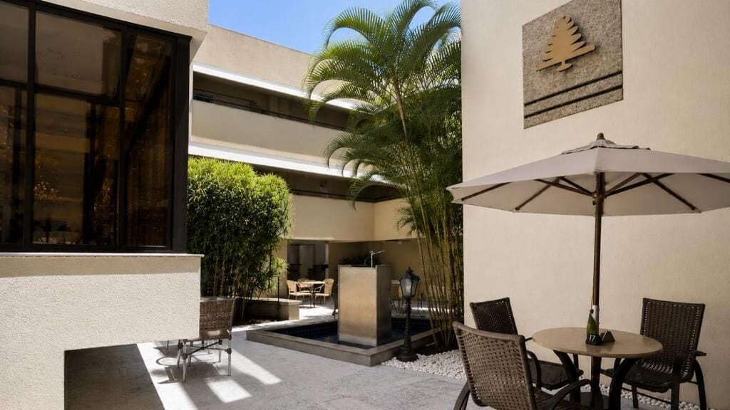 Um pátio com piscina, área de estar ao ar livre e um grande guarda-sol.