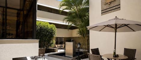 Um pátio com piscina, área de estar ao ar livre e um grande guarda-sol.