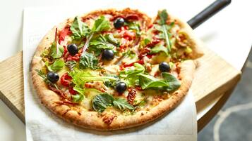 Pizza sobre uma tábua de madeira, com um jornal por baixo.