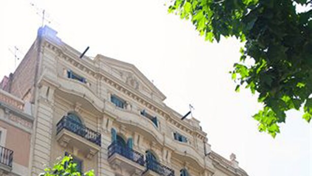 Um edifício com vários andares e varandas, com uma placa que indica 