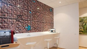 Uma área de recepção com parede estampada, um balcão com um laptop e três banquetas.