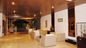 Um hall amplo com piso de madeira, várias áreas de estar e um espelho grande na parede.
