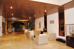 Um hall amplo com piso de madeira, várias áreas de estar e um espelho grande na parede.