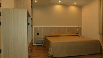 Quarto com cama, mesas de cabeceira, guarda-roupa e piso de madeira.