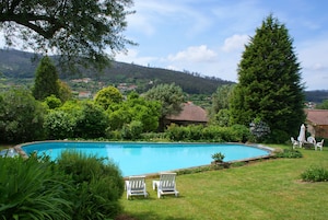 Piscina rodeada por vegetação exuberante e vista para uma paisagem montanhosa.