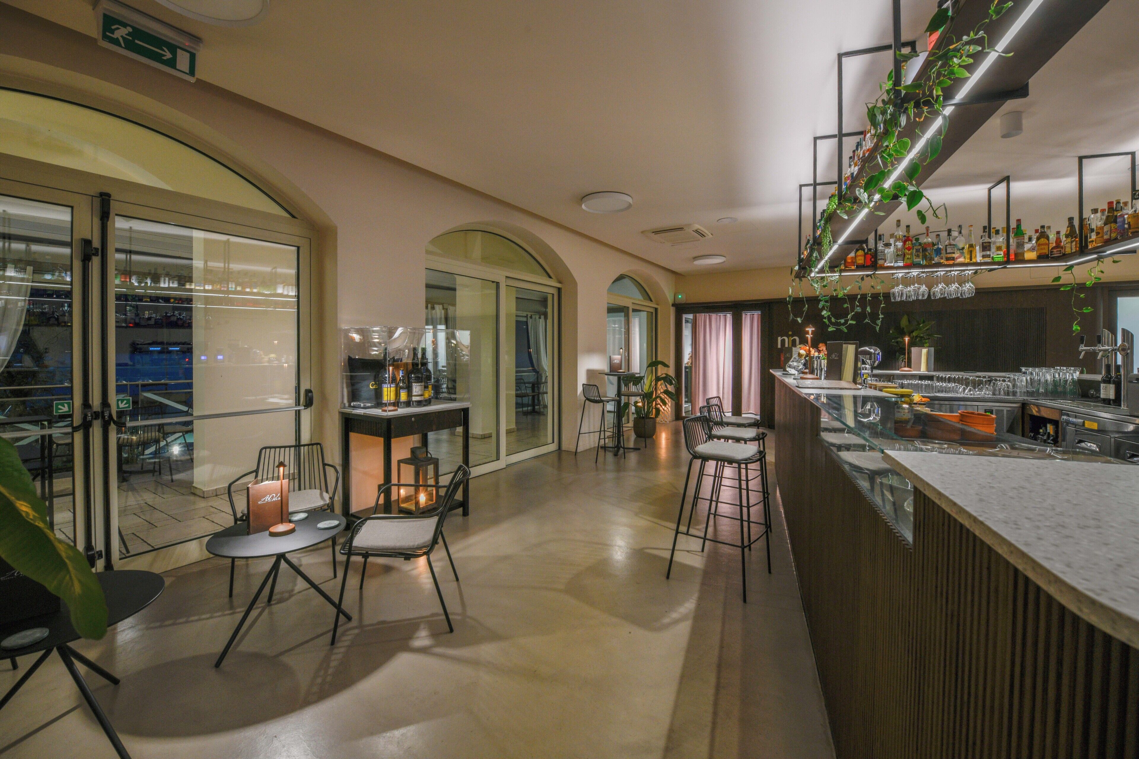 Uma área de bar com banquetas, balcão e prateleiras com garrafas.