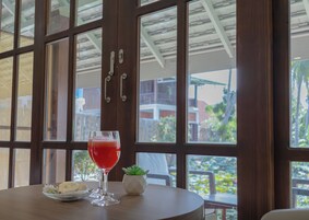 Uma mesa com um copo de bebida vermelha, um prato de comida e uma pequena planta.
