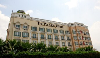 Um hotel de vários andares com design arquitetônico clássico, com varandas e uma placa de destaque com a inscrição "The Plaza Hotel".