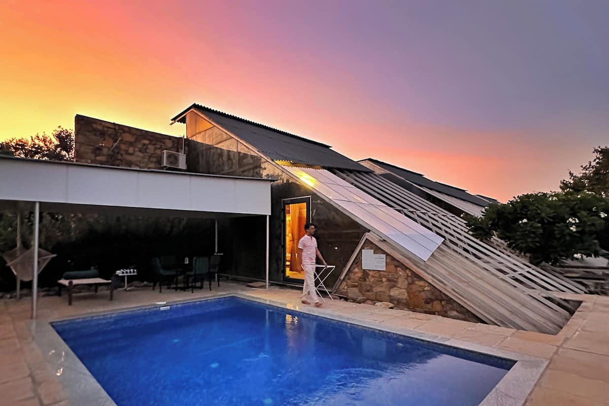 Uma casa moderna com piscina, paredes de pedra e um espaço de varanda coberto.