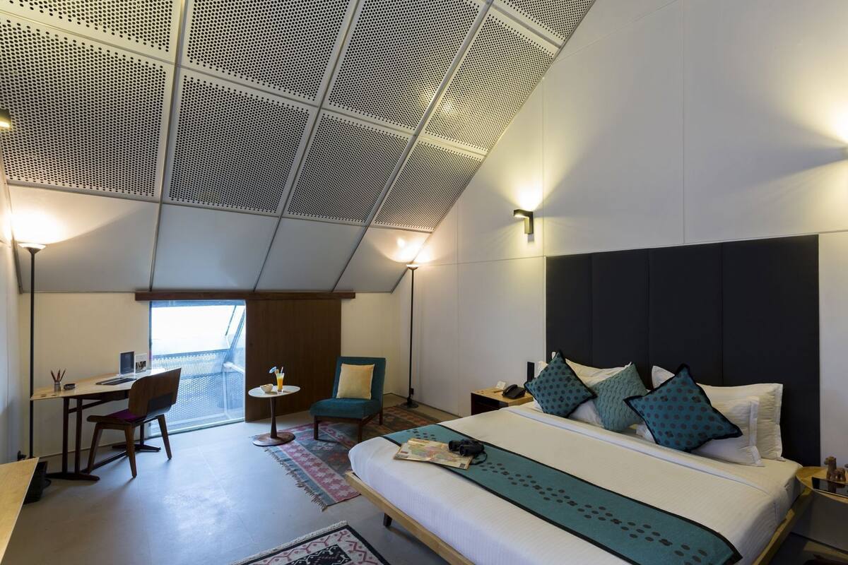 Quarto de hotel moderno com uma cama grande, uma escrivaninha e uma cadeira.