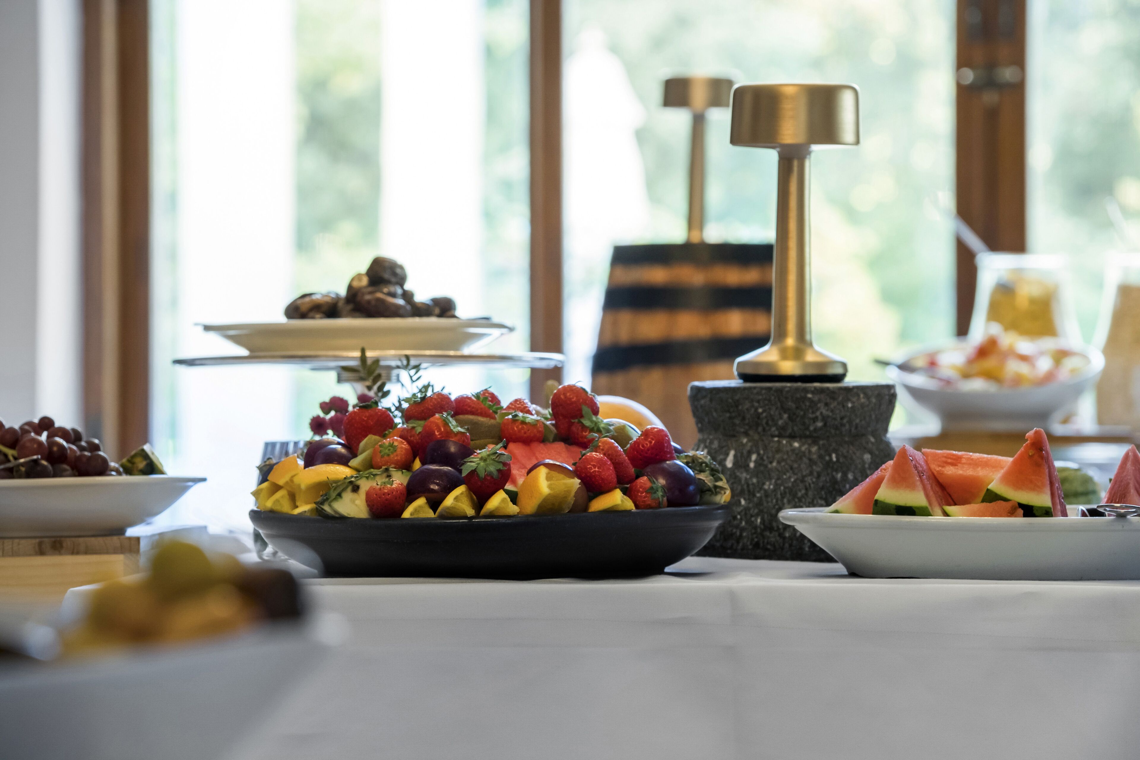Uma mesa de buffet com diversas frutas e um abajur de metal decorativo.