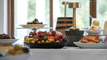 Uma mesa de buffet com diversas frutas e um abajur de metal decorativo.