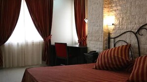 Quarto de hotel com cama, escrivaninha e cadeira.