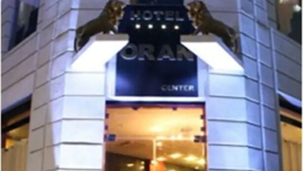 Entrada de hotel com uma placa que diz 'HOTEL CENTER' e uma estátua de leão sobre a porta.