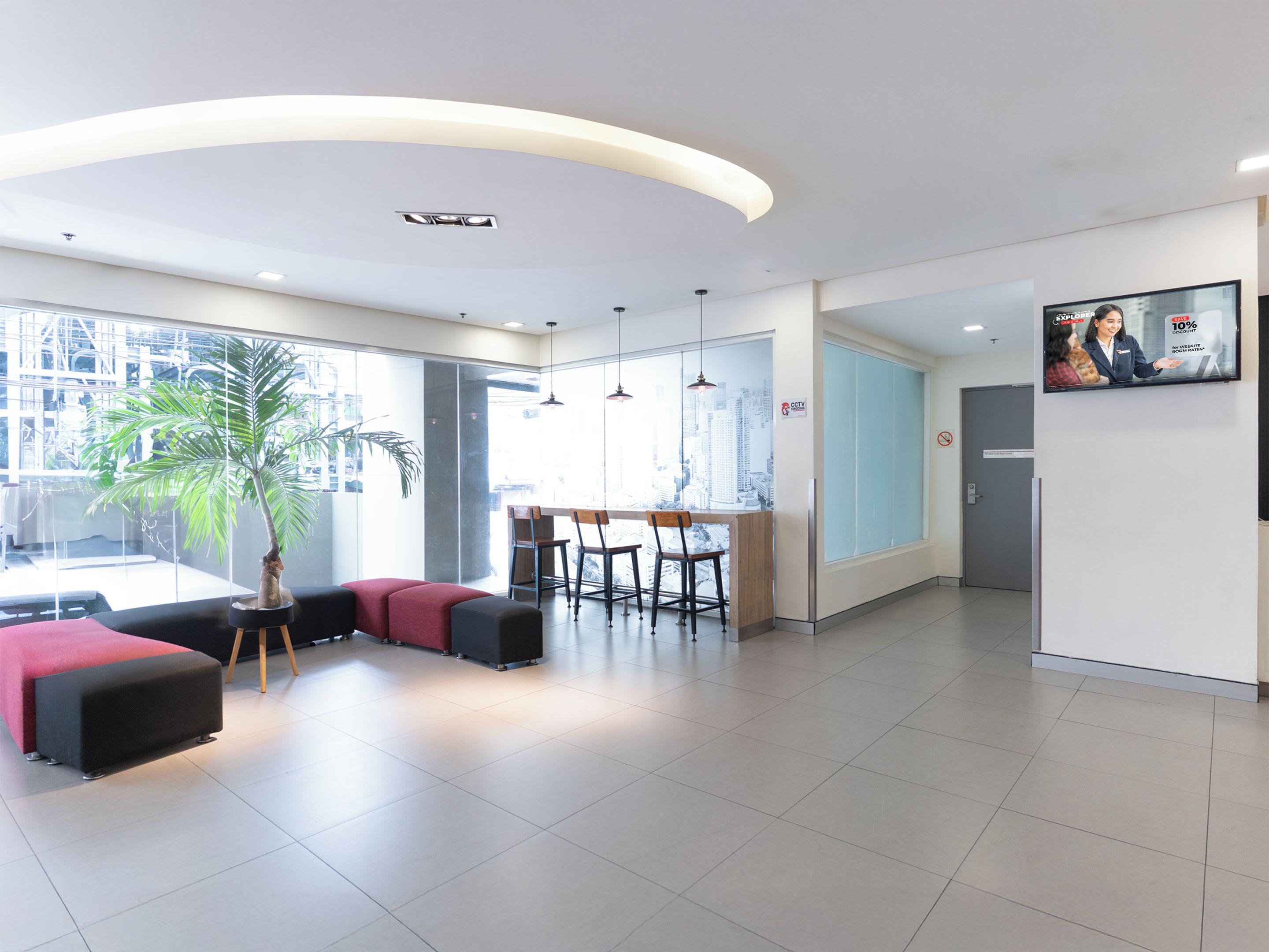 Um hall de hotel moderno com área de estar, bar e uma grande janela com vista para a cidade.