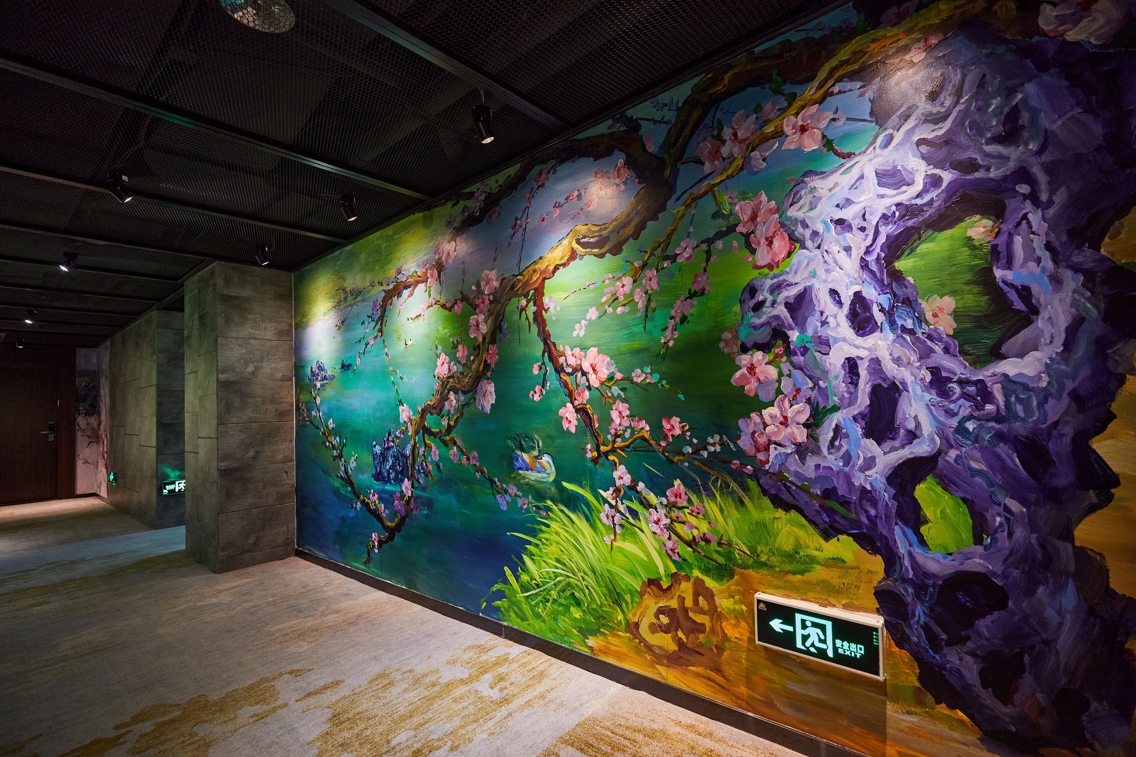 Um corredor com um grande mural de uma árvore florida em tons de rosa e verde.