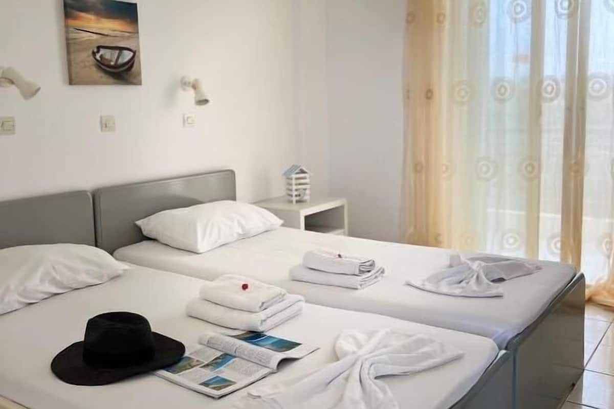 Quarto de hotel com duas camas, um quadro na parede e uma janela com cortinas.