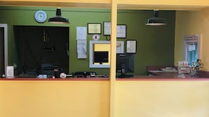 Uma área de recepção com balcão, computador e diversos documentos na parede.