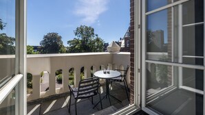 Uma varanda com mesa e cadeiras, vista do céu e um prédio ao fundo.