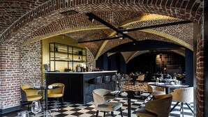 Um restaurante com chão xadrez, paredes de tijolo e um espaço de bar.
