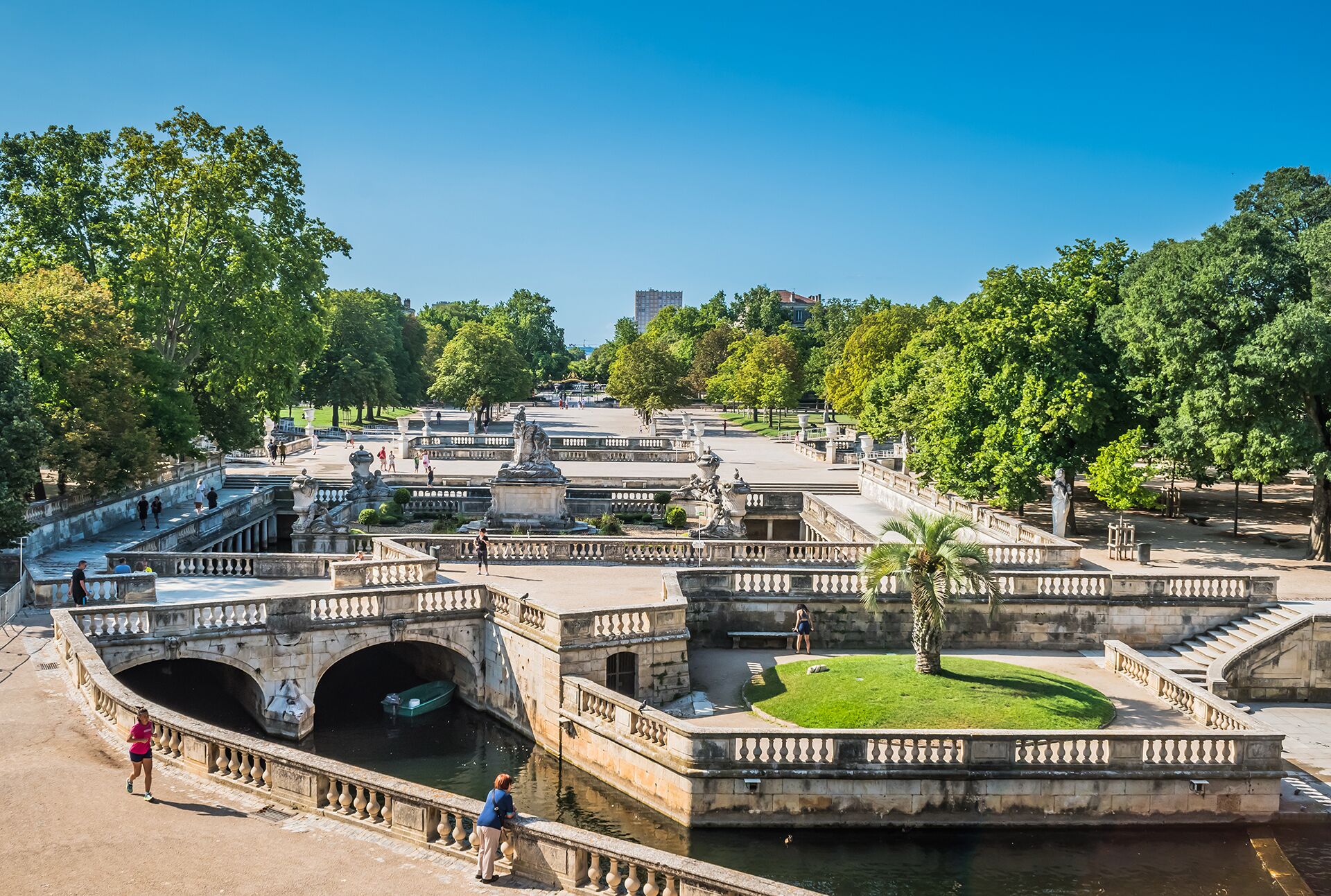 Um parque histórico com pontes de pedra, estátuas e um canal.