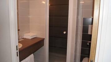 Uma casa de banho com cabine de duche, lavatório com toalha e sanita.