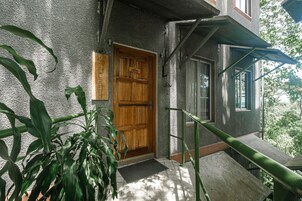 Uma porta de madeira com um letreiro, uma escadaria com corrimão verde e um vaso de planta.