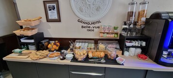 Um buffet de café da manhã com pães, bolos, frutas e acompanhamentos variados.
