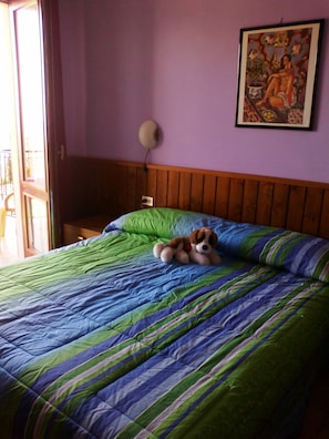 Uma cama com colcha listrada, cabeceira de madeira e um quadro na parede.