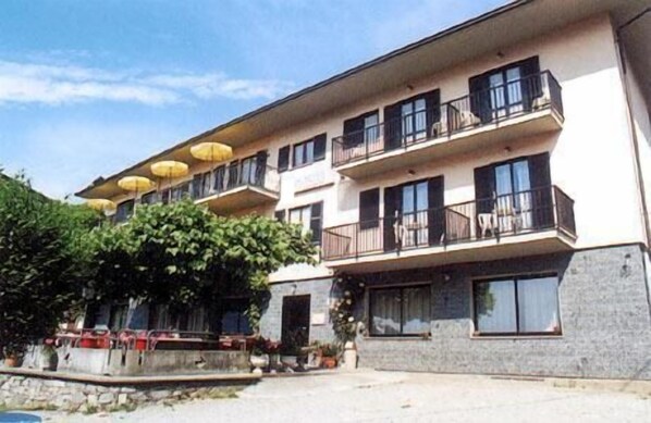 Um hotel com vários andares, varandas, fachada de pedra e área de estar externa.