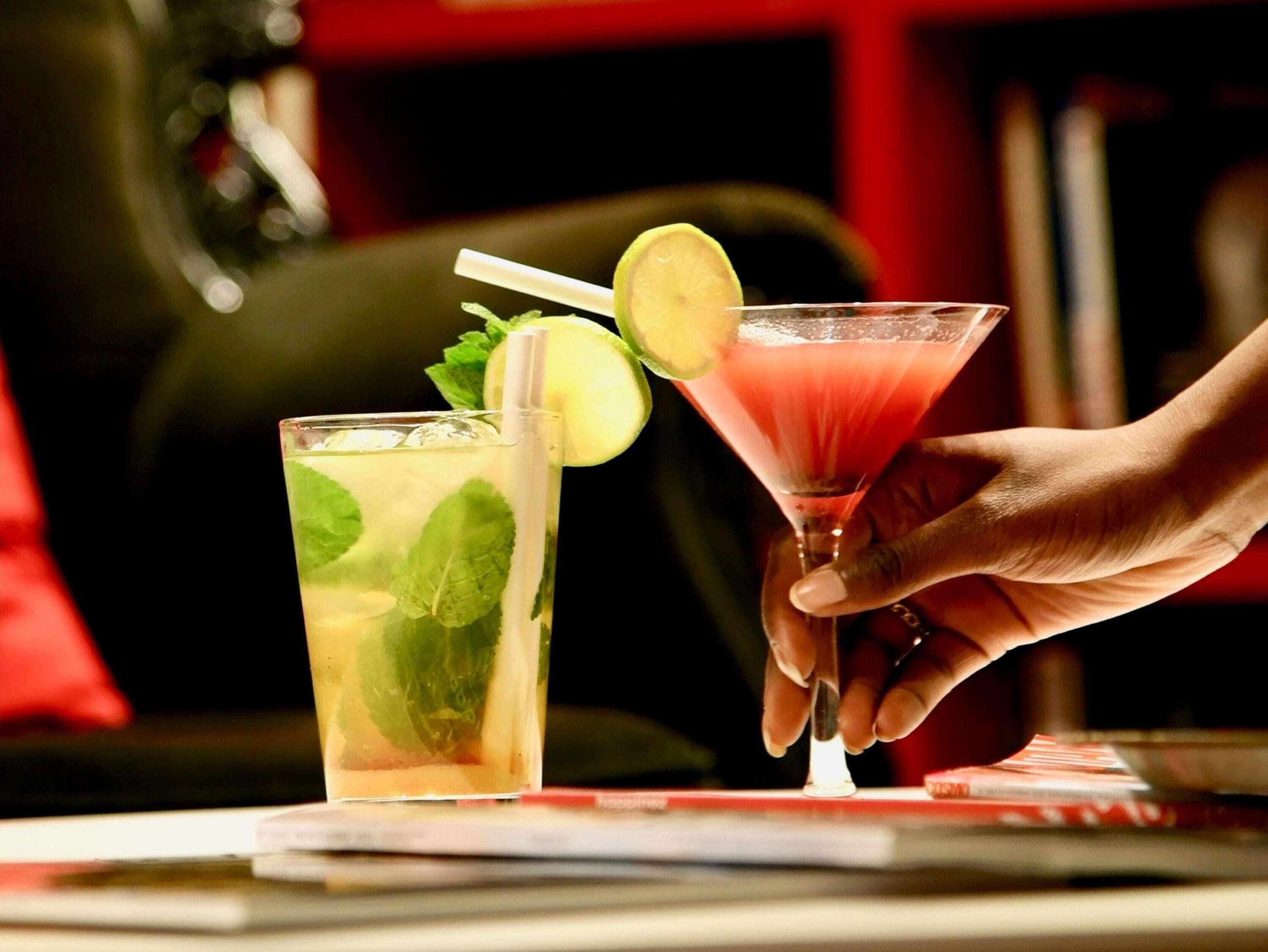 Dois cocktails numa mesa, com uma mão a alcançar um deles.
