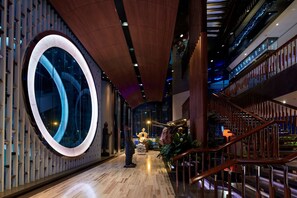 Interior moderno com um domo circular, soalho de madeira e escada com grades de metal.