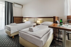 Quarto de hotel com duas camas, uma mesa e uma cadeira.