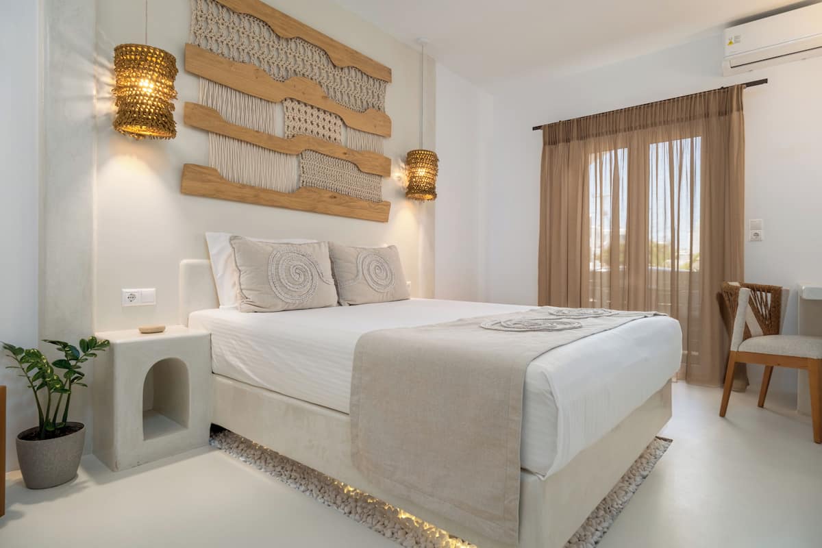 Quarto moderno com cama grande, um espaço de estar pequeno e uma peça decorativa na parede.