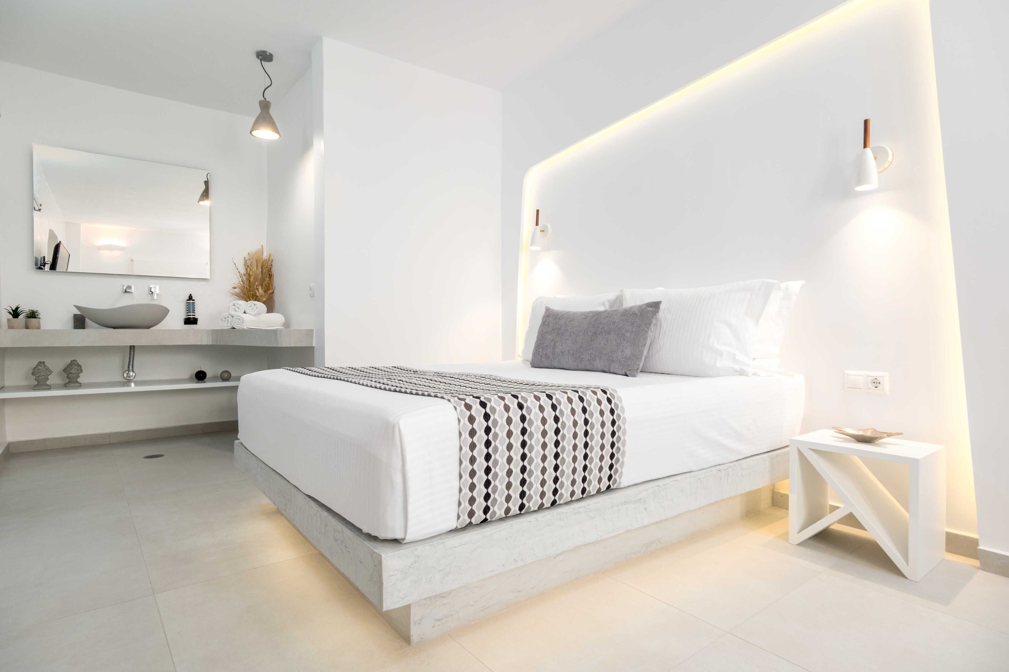 Quarto moderno com uma cama grande, mesas de cabeceira, uma toucador com espelho e um aplique.