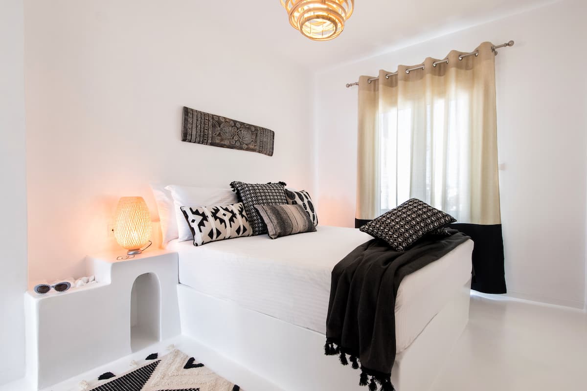 Quarto bem arrumado com cama, abajur e um objeto decorativo na parede.