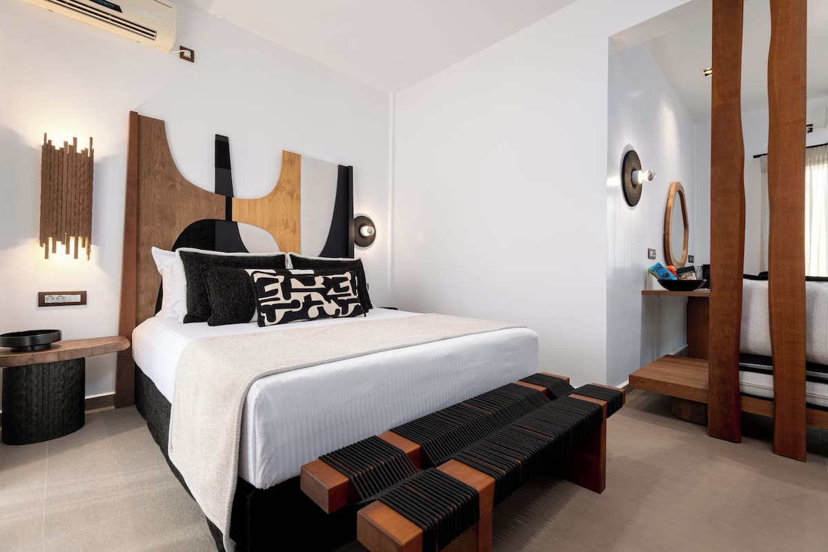 Quarto moderno com uma cama grande, uma mesa de cabeceira, um banco e um espelho.