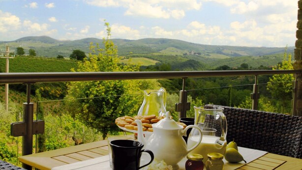 Mesa com itens de café da manhã e vista para colinas ondulantes.