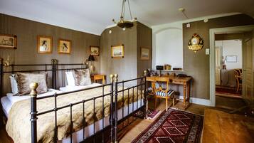 Quarto com cama, escrivaninha, cadeira, tapete e lustre.