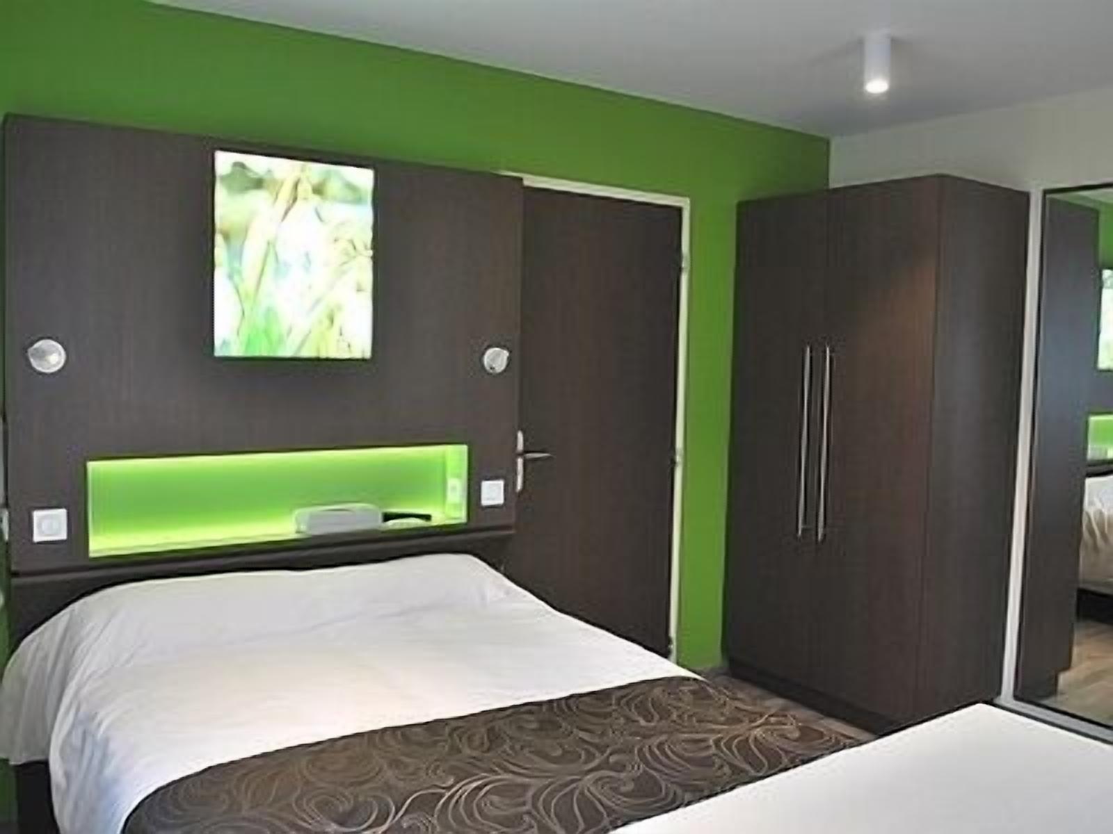 Quarto moderno com cama, parede de destaque verde e guarda-roupa espaçoso.