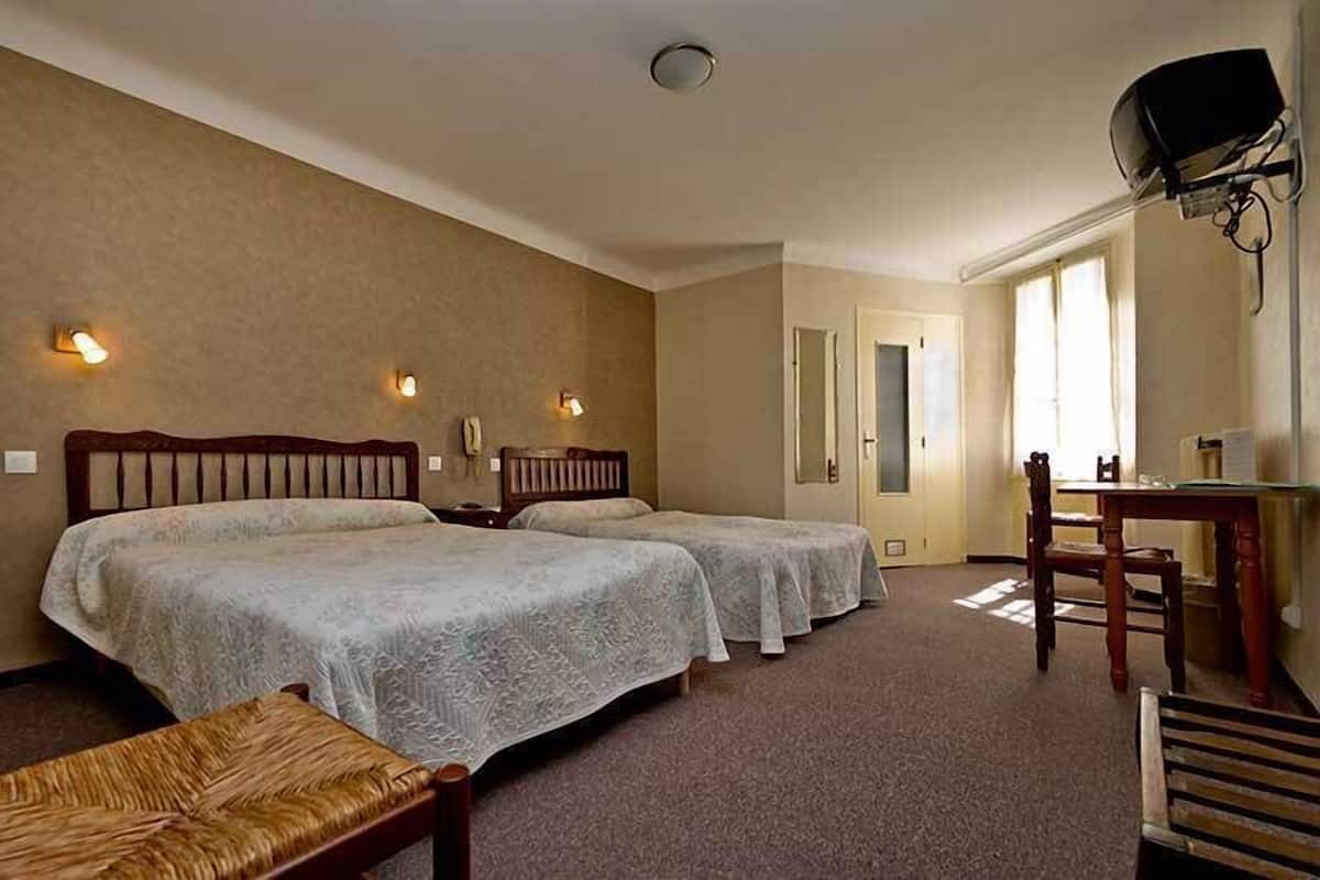 Quarto de hotel com duas camas, uma escrivaninha, uma cadeira e uma televisão.