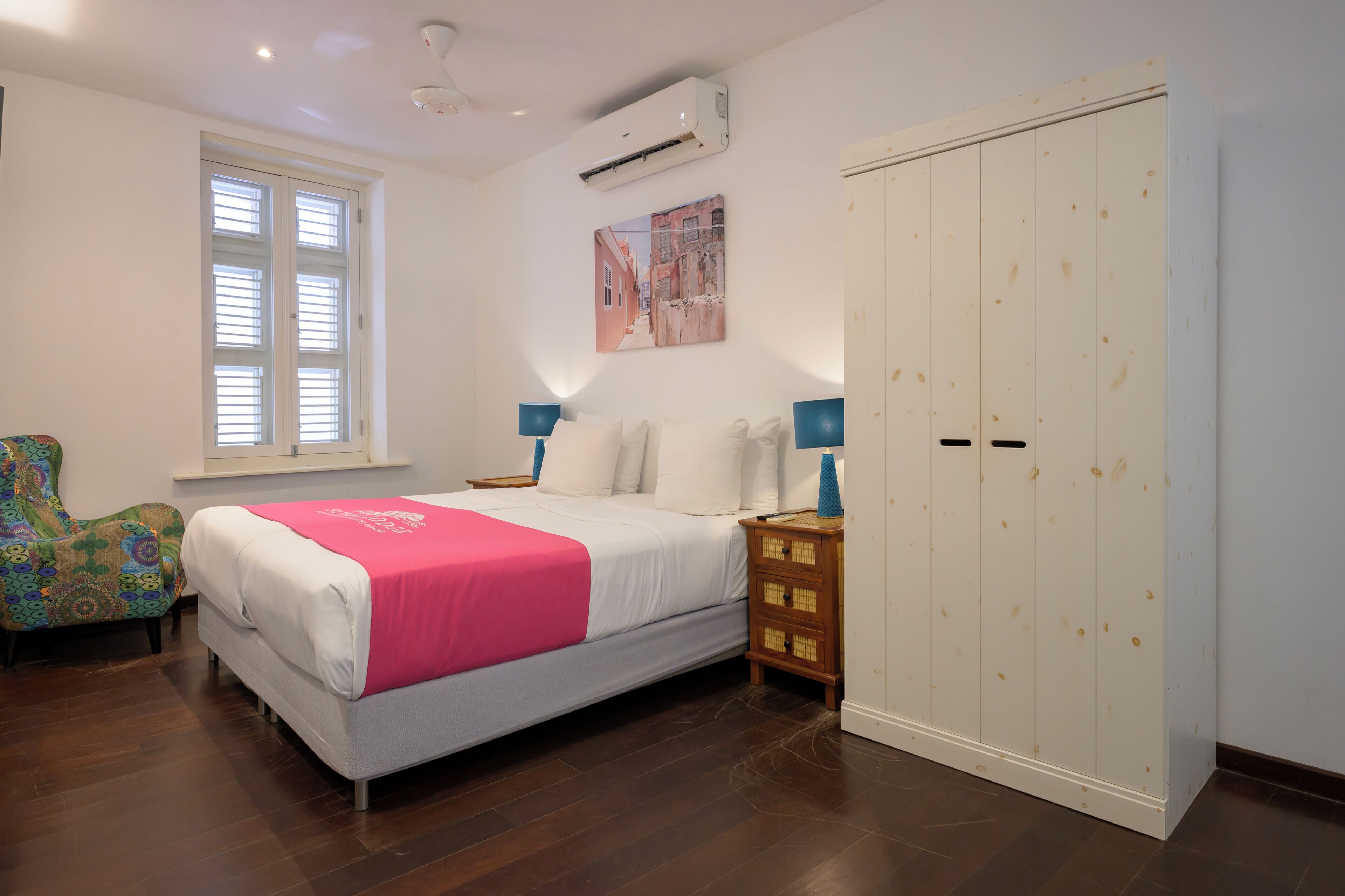 Quarto com cama, guarda-roupa, cadeira e ar condicionado.