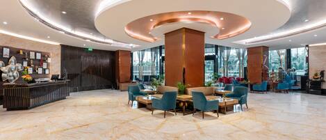 Um lobby amplo, com balcão de recepção, área de estar e grandes janelas que oferecem vistas.