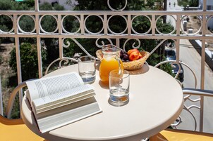 Uma mesa com um livro, um copo de sumo de laranja e uma cesta de frutas.