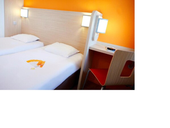 Quarto de hotel com duas camas, uma escrivaninha e uma cadeira.