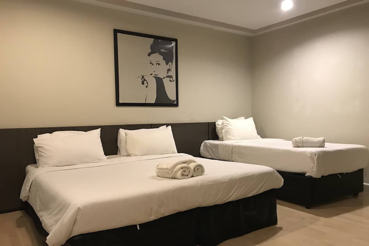 Quarto de hotel com duas camas, cada uma com roupa de cama e almofadas brancas, e uma grande obra de arte emoldurada na parede.
