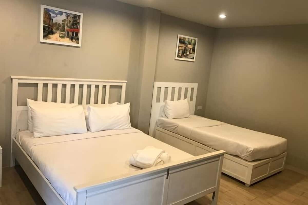 Quarto com duas camas, cada uma com cabeceiras e roupa de cama brancas.
