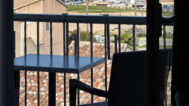 Uma varanda com vista para o mar, uma mesa e uma cadeira.