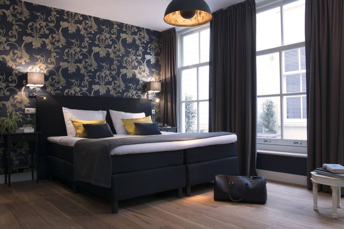 Quarto moderno com uma cama grande, cortinas escuras e uma janela com vista.