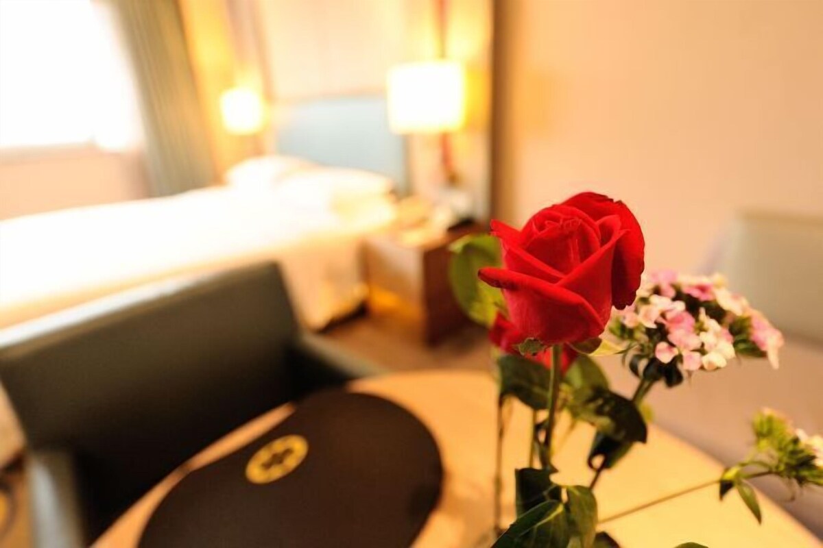 Quarto de hotel com uma cama, uma escrivaninha e um computador portátil.